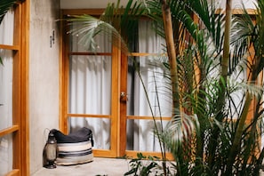 Uma porta de madeira com uma placa de número, uma mala listrada em preto e branco, e um candeeiro no chão.