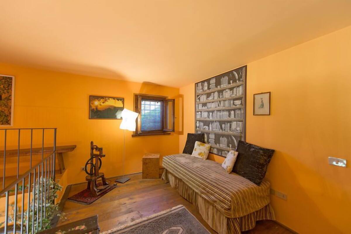 Um quarto com uma cama, uma estante, uma janela e uma escada.