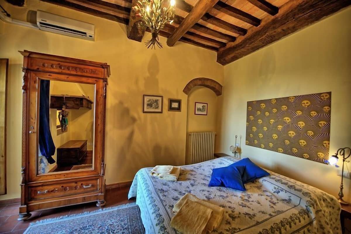 Quarto com guarda-roupa de madeira, cama com colcha florida e parede com padrão de caveira.