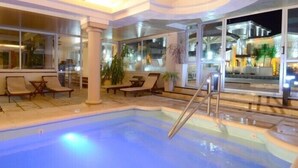 Área interna de piscina com espreguiçadeiras e escadaria que dá acesso a uma área externa.