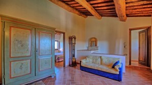 Quarto com teto de madeira, um armário verde com painéis decorativos, um sofá azul e um relógio de chão alto.
