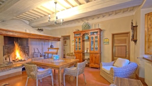 Uma sala de estar aconchegante com lareira, móveis de vime e um armário de madeira.