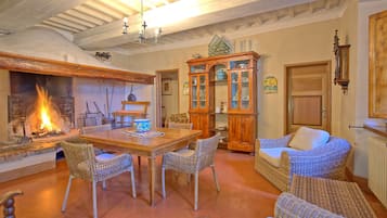 Uma sala de estar aconchegante com lareira, móveis de vime e um armário de madeira.