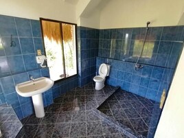 Casa de banho com lavatório, sanita e chuveiro.
