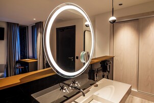 Uma casa de banho moderna com um espelho grande, uma toucador com lavatório e uma área de chuveiro.