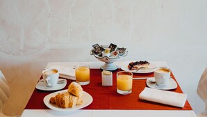 Uma mesa de café da manhã com croissants, café e suco de laranja.