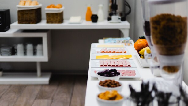 Uma mesa de buffet com diversos alimentos e uma máquina de café.