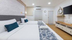 Quarto de hotel com duas camas, televisão, relógio e janela com cortinas.