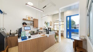 Um café moderno com balcão de madeira, um sistema POS digital e uma porta azul que dá para o exterior.