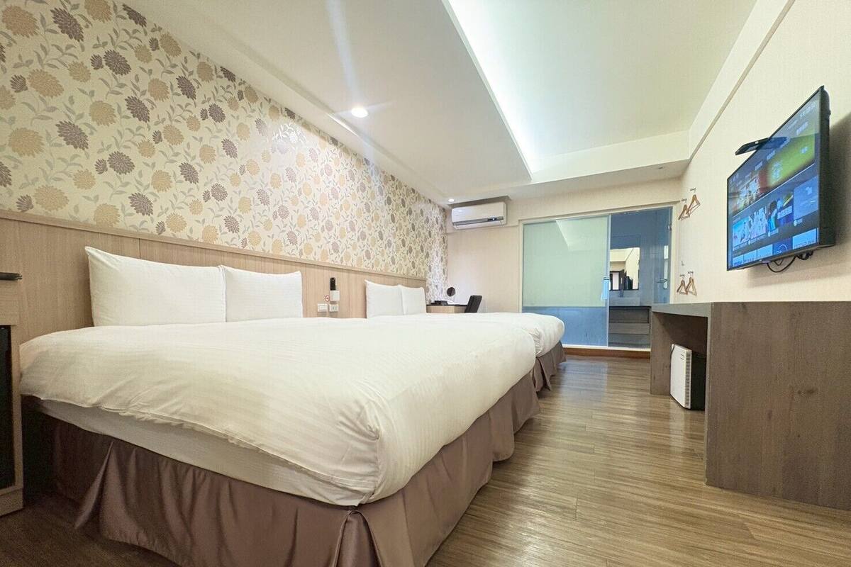 Quarto de hotel com uma cama grande, televisão e secretária com cadeira.