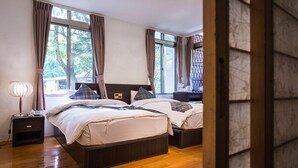 Quarto com duas camas, piso de madeira e grandes janelas com cortinas.