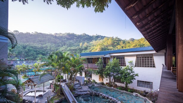 Um resort com área de piscina, deck de madeira e vista para uma encosta arborizada.