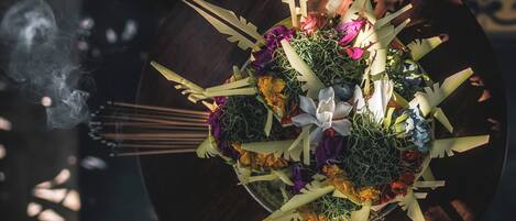 Um close-up de uma mão segurando um buquê de flores com folhas verdes e flores de várias cores, possivelmente para uma cerimônia.