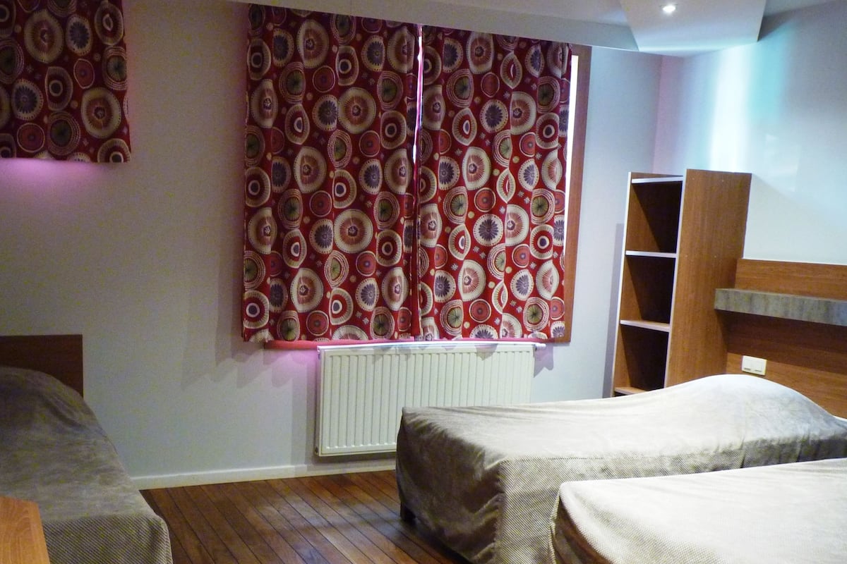 Quarto com duas camas, um radiador e um estante.