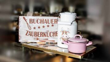Uma bancada de cozinha com uma placa que diz "BUCHAUER ZAUBERKÜCHE" e uma panela rosa com tampa.