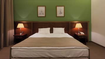 Quarto de hotel com uma cama grande, duas mesas de cabeceira com luminárias e duas imagens emolduradas na parede.