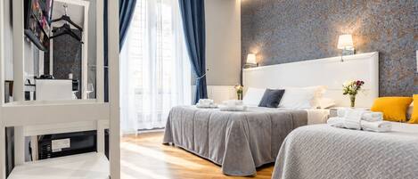 Quarto de hotel com duas camas, um espelho grande, um guarda-roupa e parede com padrão.