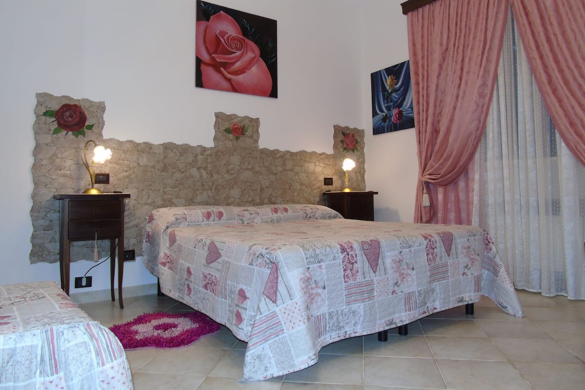 Quarto com duas camas, parede de pedra e detalhes florais.