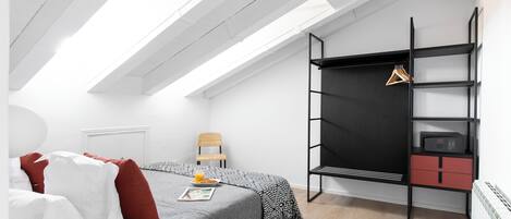 Quarto com cama, cadeira, escrivaninha e estante.