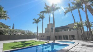 Um edifício moderno com piscina rodeada por palmeiras.