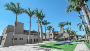 Pátio com palmeiras, piscina e edifícios modernos.