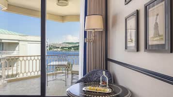 Quarto de hotel com varanda, uma mesa com bandeja de doces e quadros nas paredes.