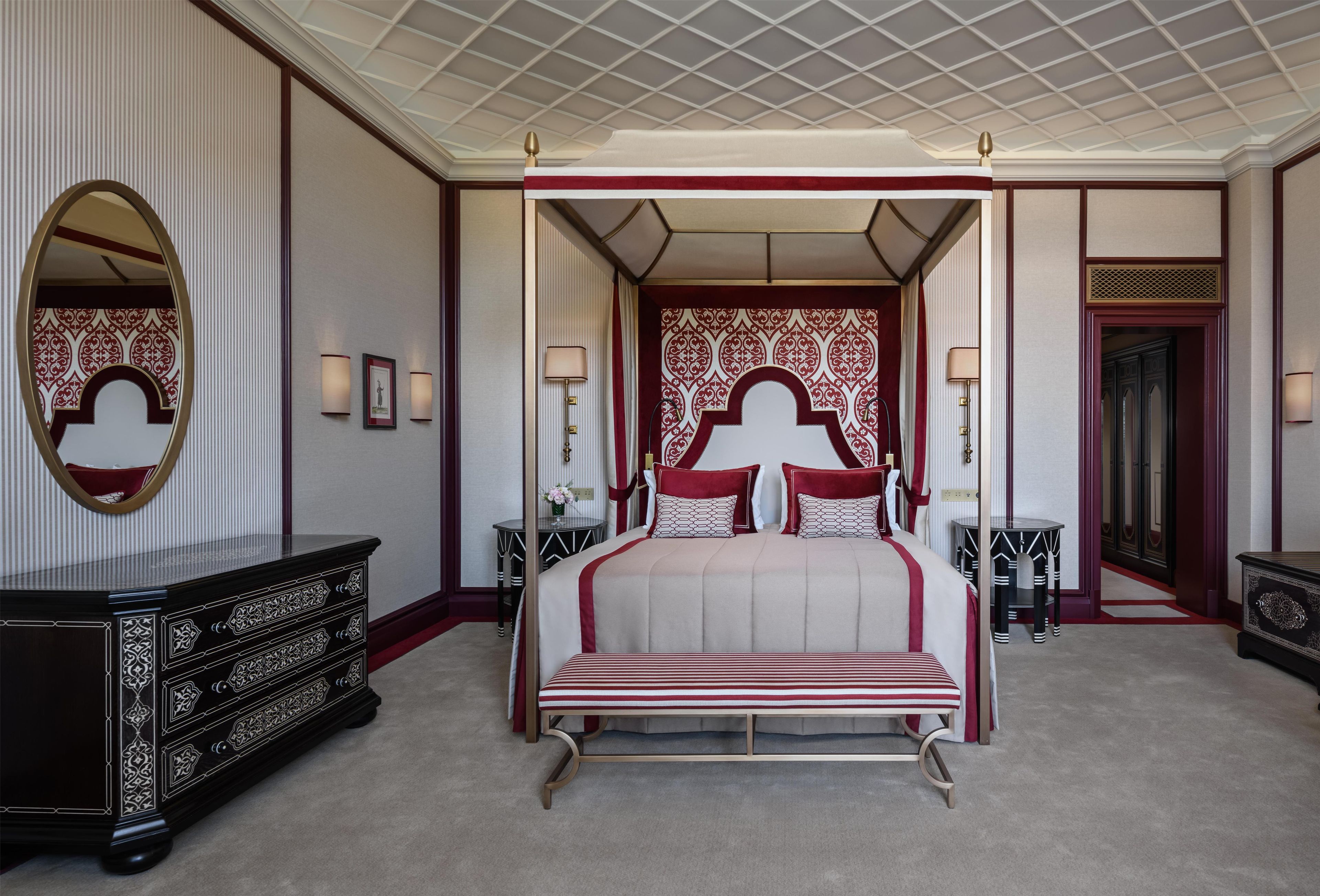 Quarto de hotel com uma cama grande, cômoda, espelho e decoração na parede.