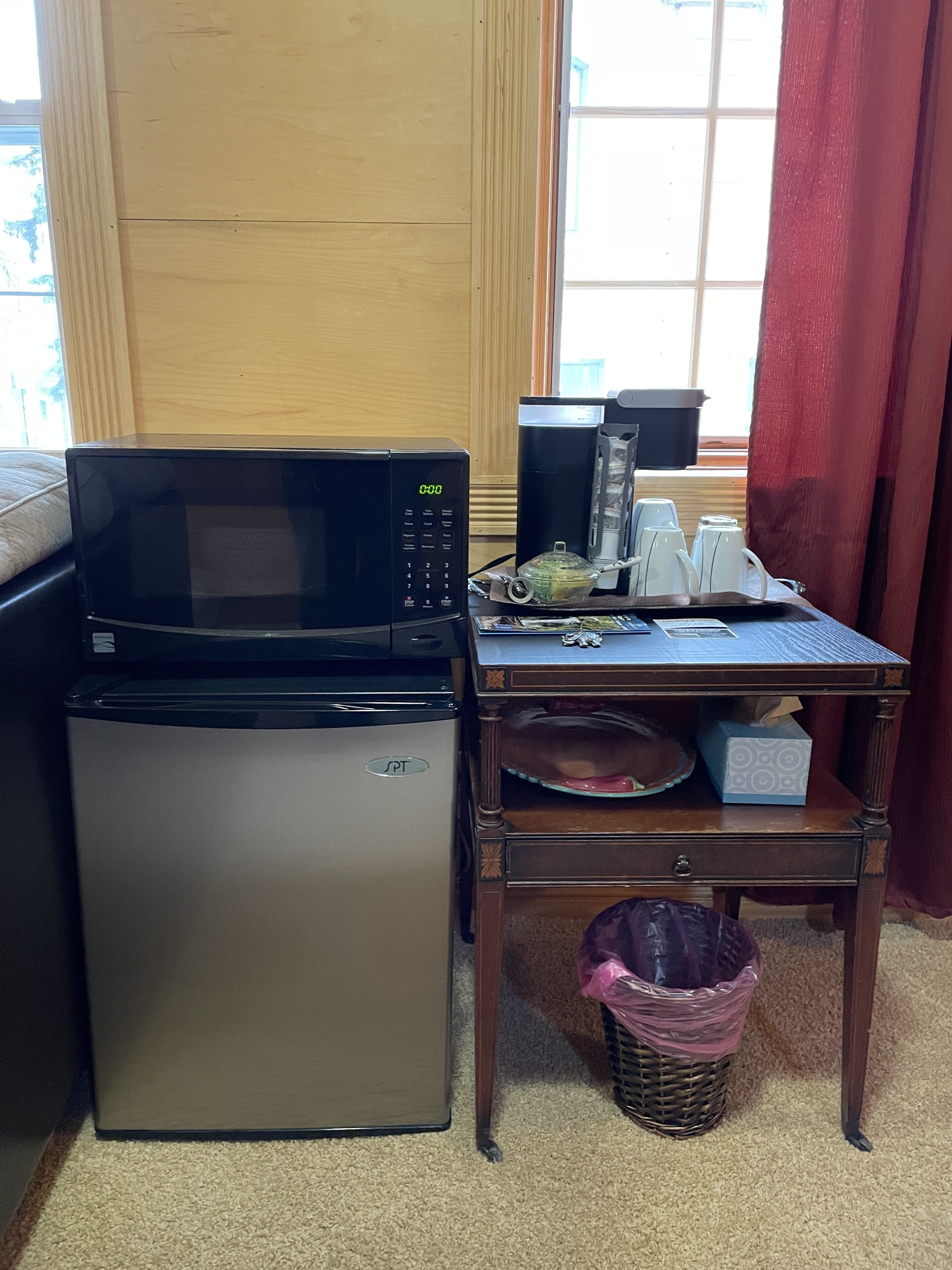 Uma cozinha compacta equipada com geladeira, micro-ondas e cafeteira.