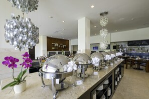 Disposição de buffet com várias estações de serviço, uma orquídea em vaso e design de interiores moderno.