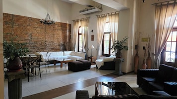 Uma sala de estar com parede de tijolos, um candelabro, um sofá, uma mesa de centro e uma planta em vaso.