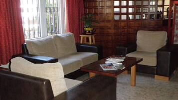 Uma sala de estar com sofá, duas poltronas, uma mesa de centro e um painel de madeira.