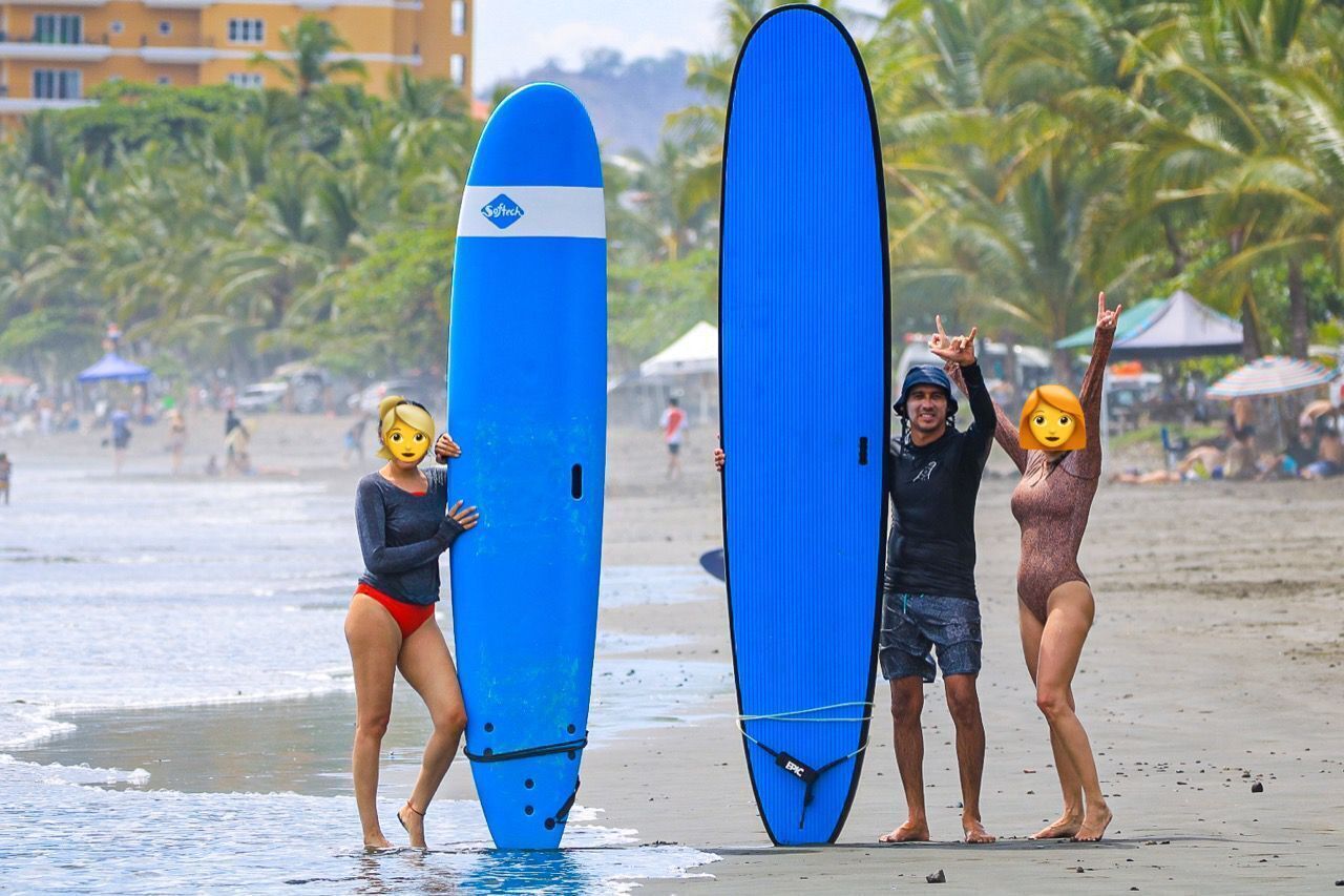 Cena de praia com pessoas segurando pranchas de surf.