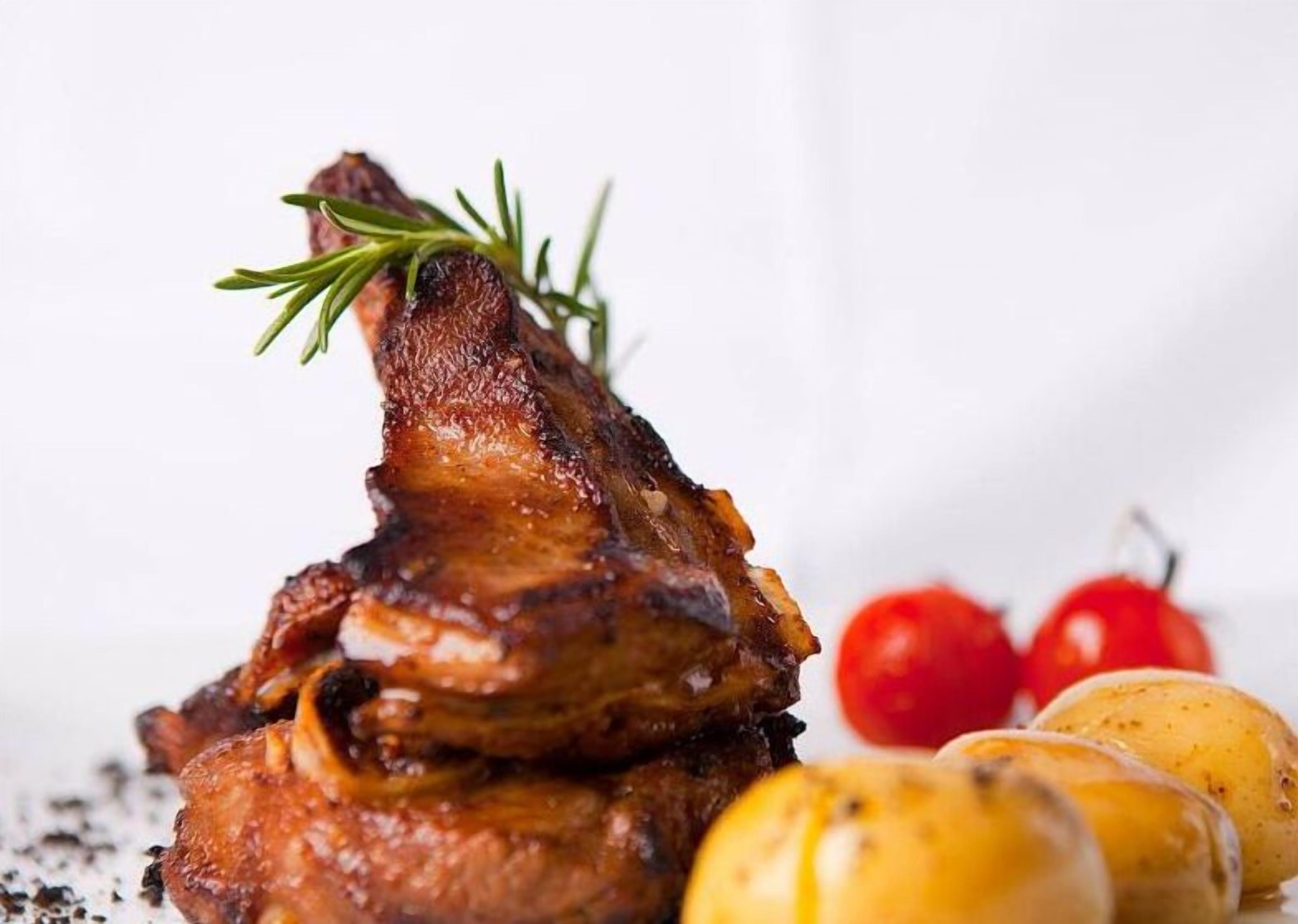 Frango assado com alecrim, acompanhado de batatas e tomates cereja assados.