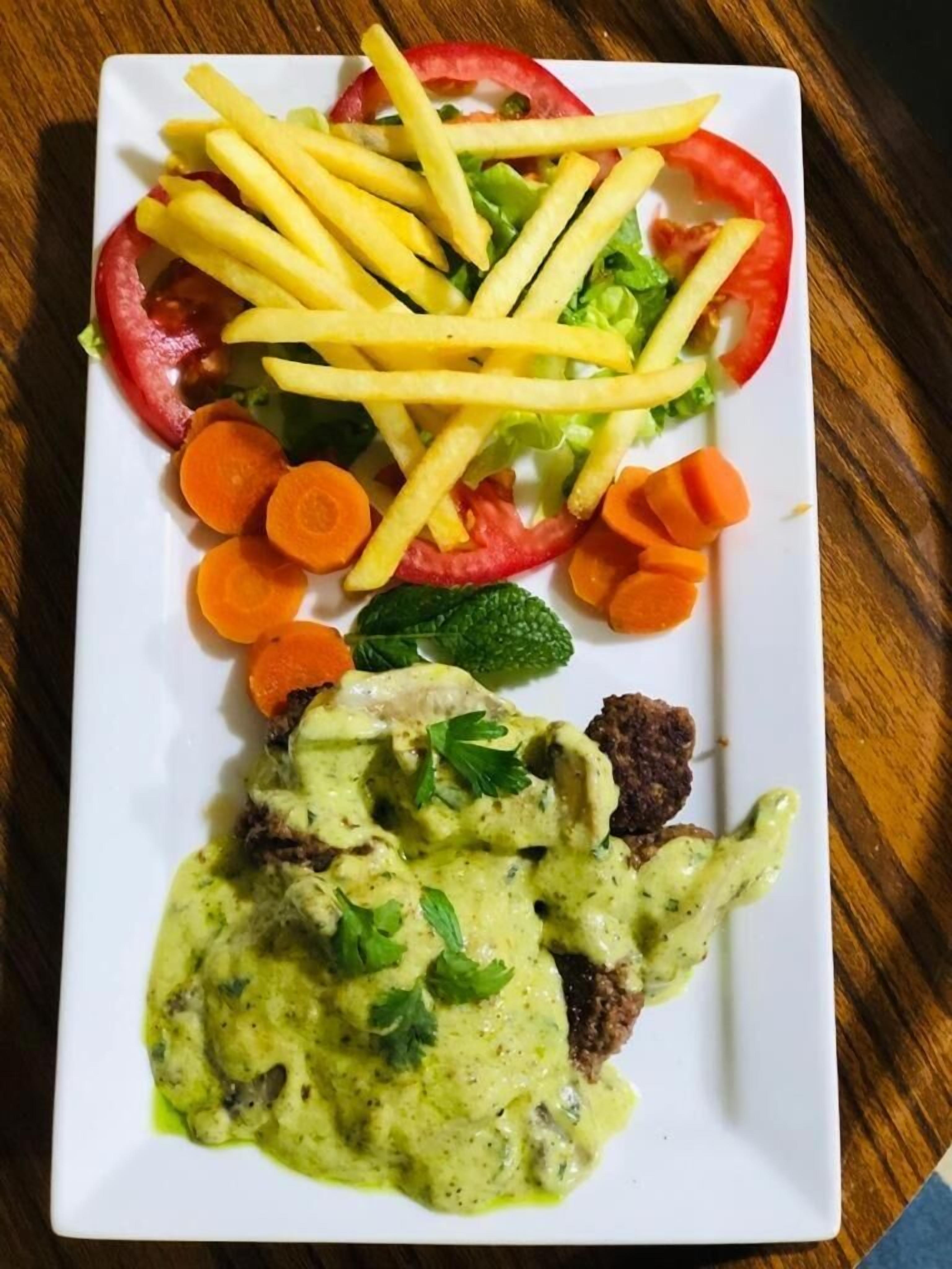 Um prato com carne, batatas fritas e diversos vegetais.