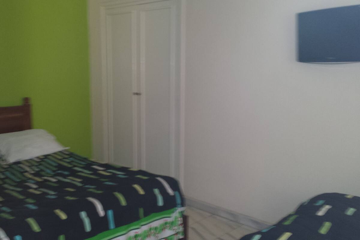 Quarto com cama, guarda-roupa e televisão na parede.