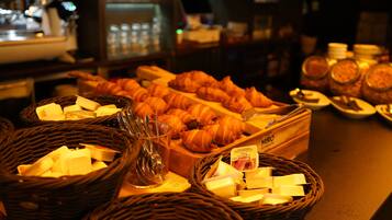 Buffet de café da manhã com croissants, queijo e cestas de pão.