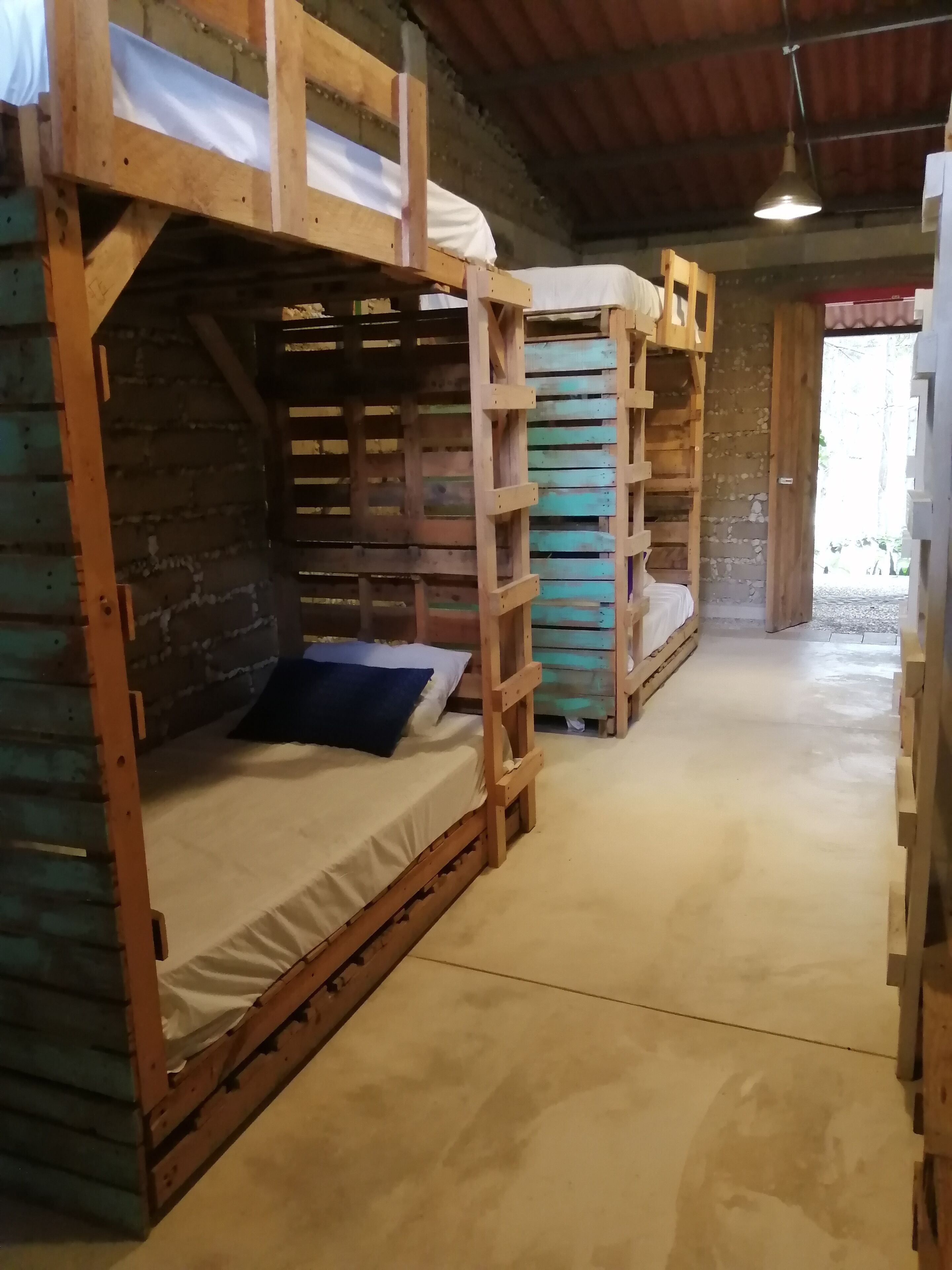 Quarto rústico com beliches de madeira e piso de concreto.