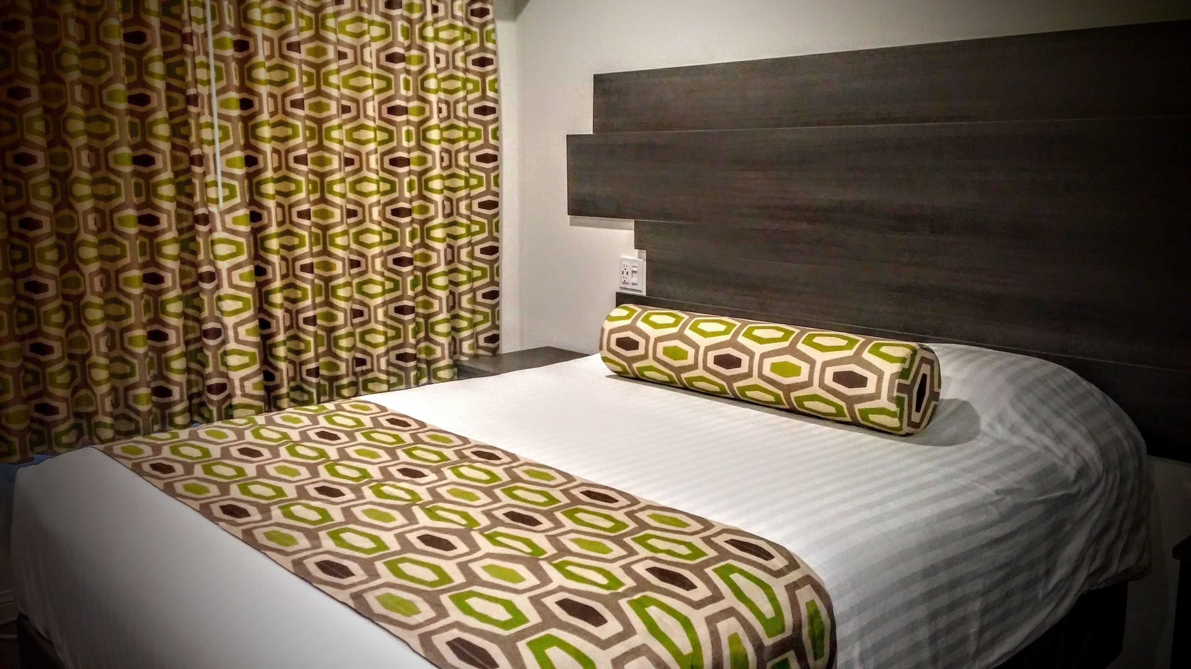 Cama bem arrumada com roupa de cama estampada, cabeceira e travesseiro.