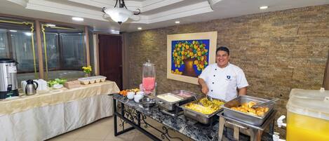 Uma mesa de buffet com diversos alimentos e um dispensador de bebidas.