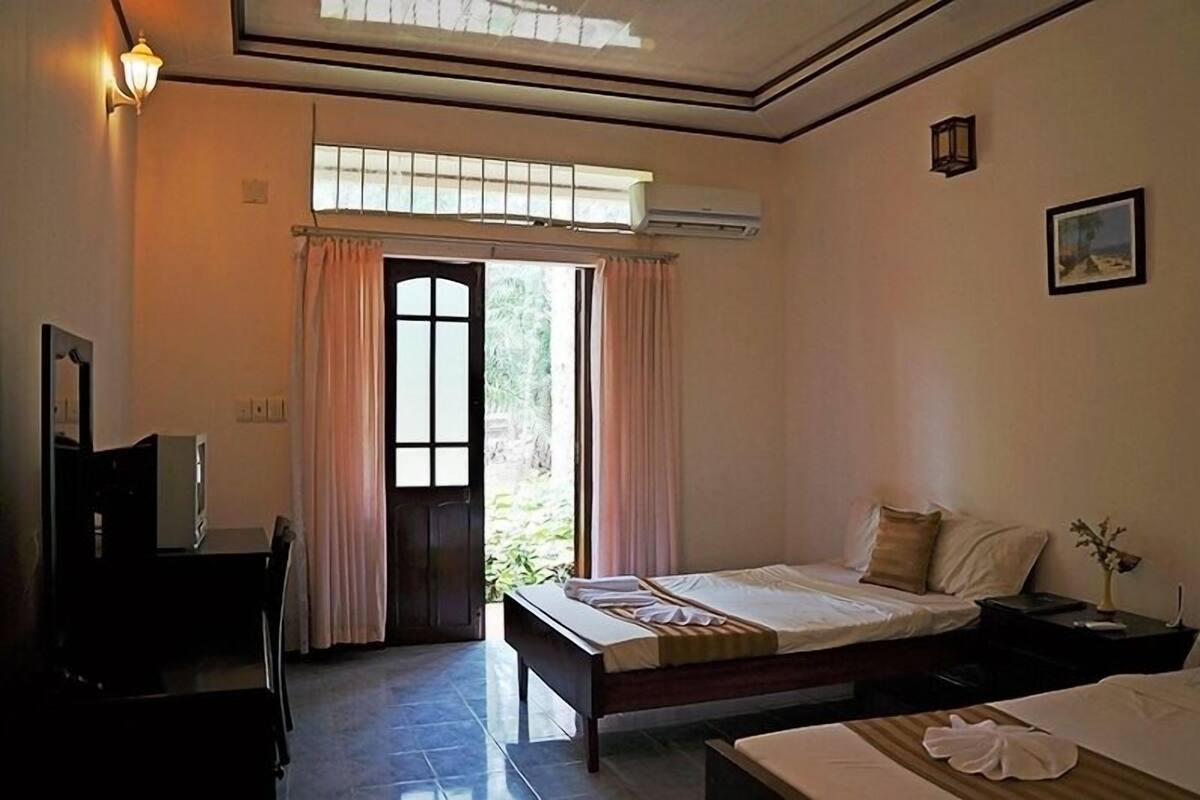 Quarto de hotel com uma cama, mesa de cabeceira e escrivaninha com cadeira.