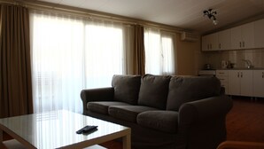 Sala de estar com sofá, mesa de centro e área de cozinha ao fundo.