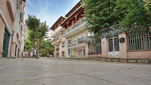 Uma rua calma com edifícios altos, céu claro e árvores.