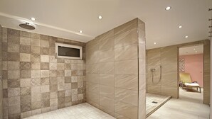 Um banheiro moderno com azulejos estampados, área de chuveiro e um espaço de estar com uma cadeira.