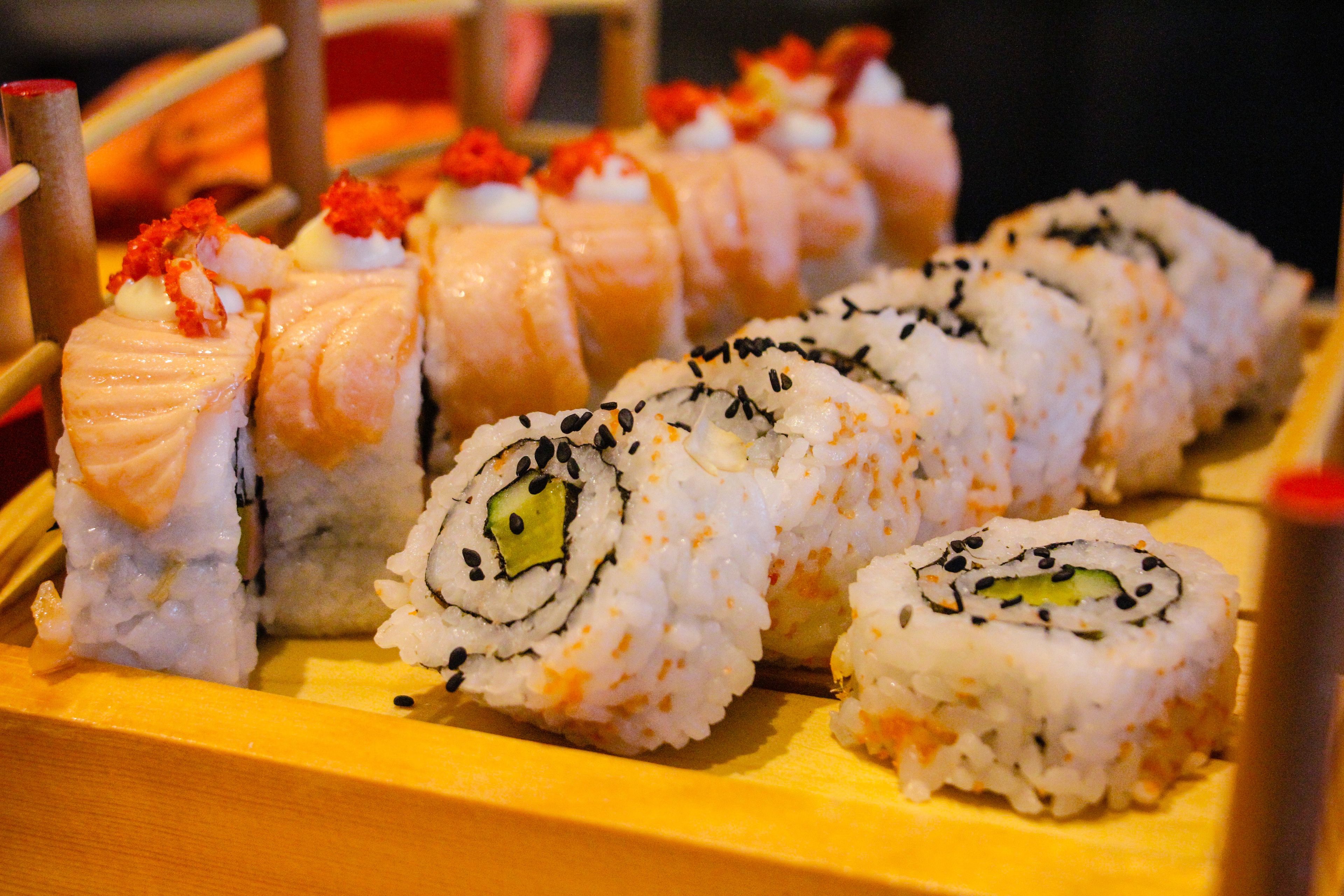Uma bandeja de sushi com rolinhos e diversos acompanhamentos e guarnições.