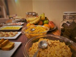 Uma mesa de buffet com diversos alimentos, incluindo frutas, cereais e pastelaria.