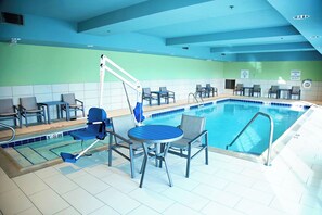 Piscina interna com trampolim, espreguiçadeiras e placa de salva-vidas.