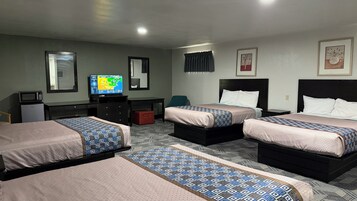 Quarto de hotel com duas camas, uma escrivaninha com computador, televisão e micro-ondas.