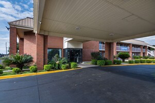 Um hotel com entrada coberta, fachada de tijolos e estacionamento.