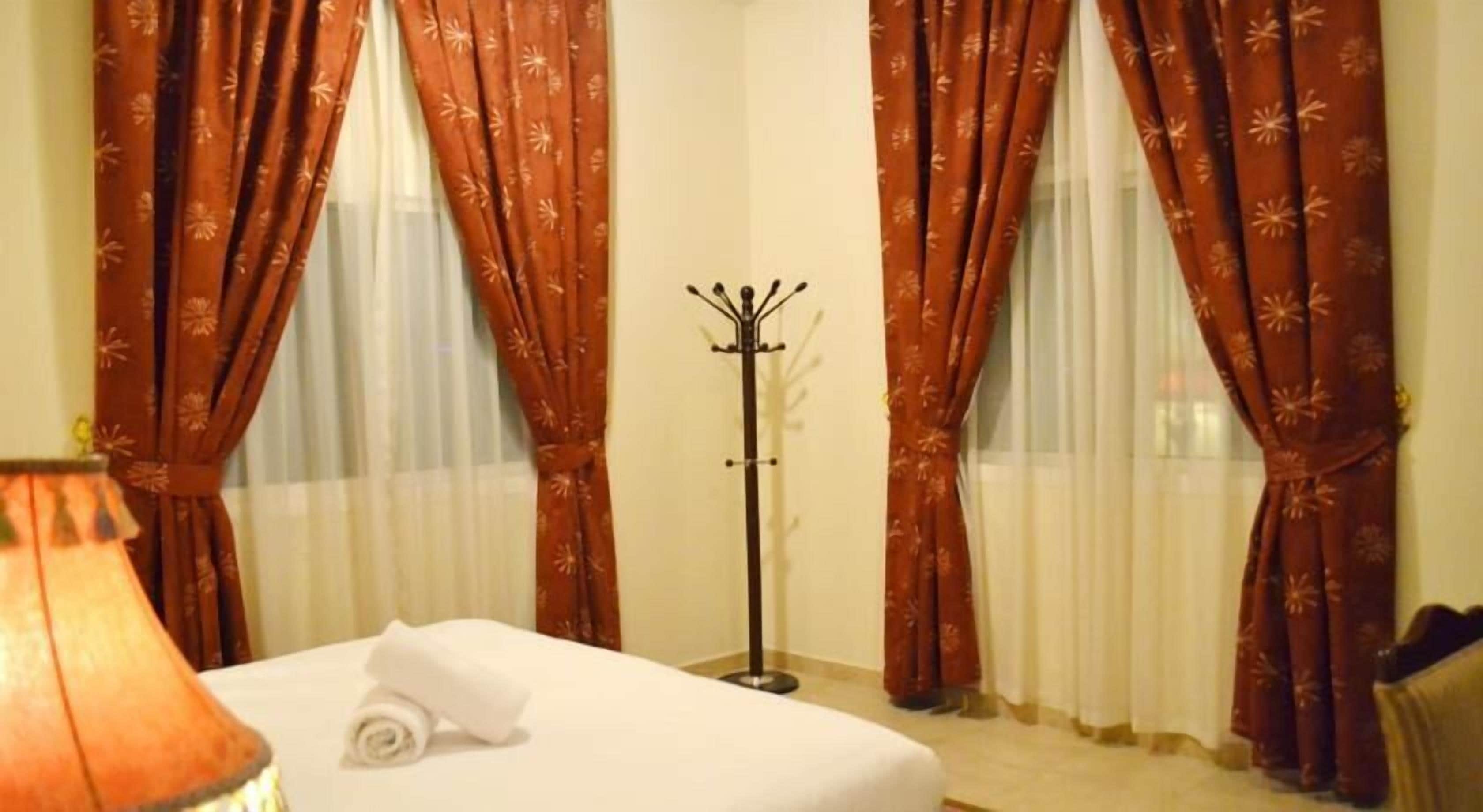 Quarto de hotel com cama, cabideiro e cortinas.