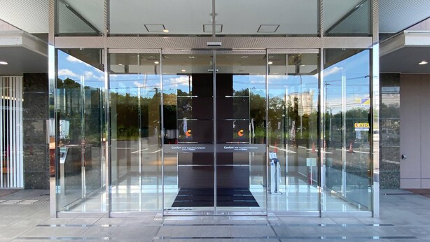 Entrada de um edifício moderno com portas de vidro e chão de azulejos.
